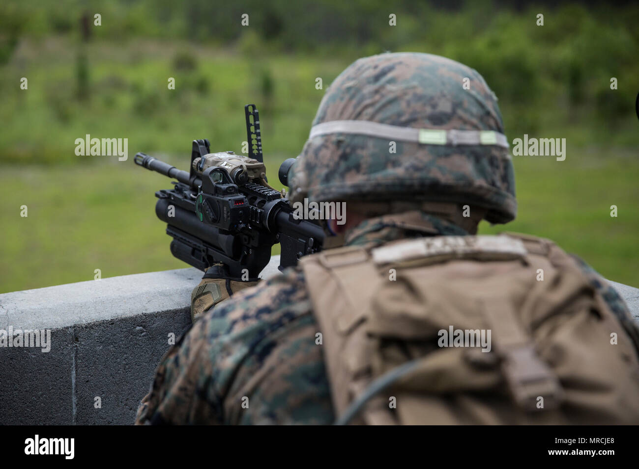 A Marine observes a target through a sight on an M320 grenade launcher ...