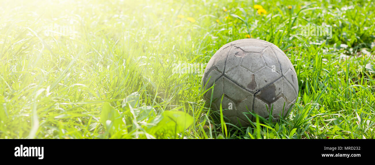 Old soccer ball forgotten in the green grass field. The football ...
