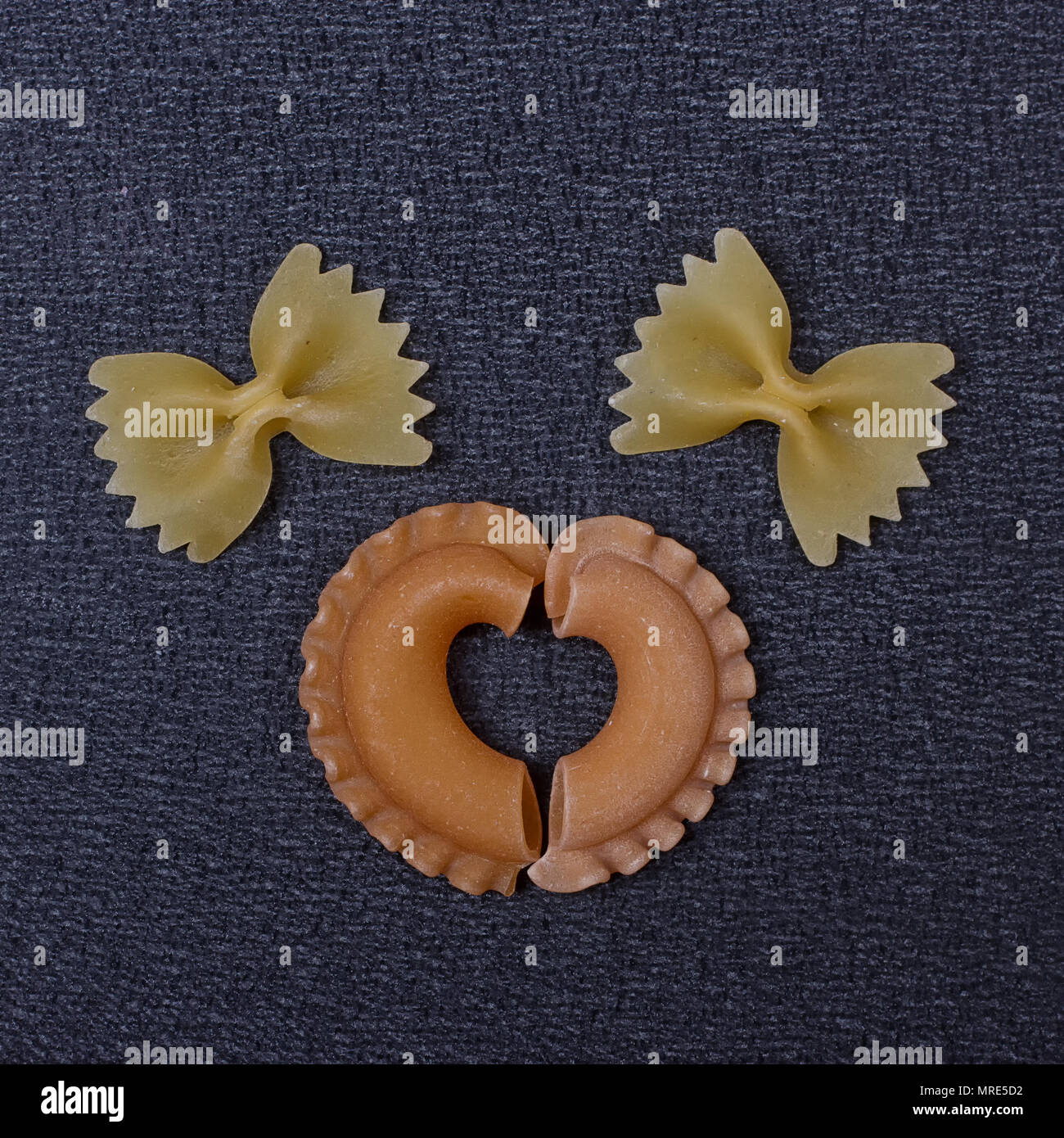 Smiling raw pasta on the black background Stock Photo - Alamy