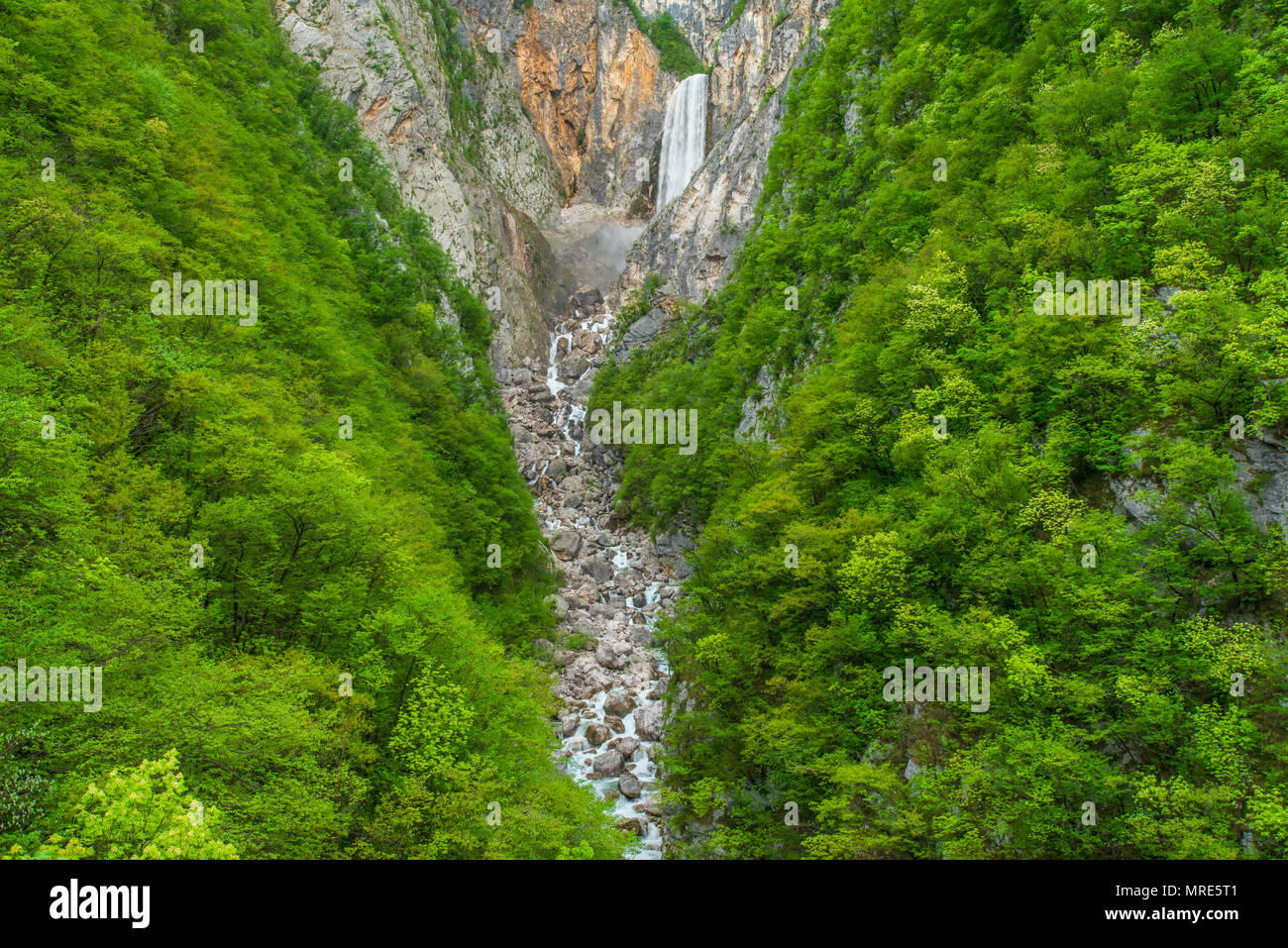 Symmetric shot of massive waterfall cascading down steep rocky slopes ...