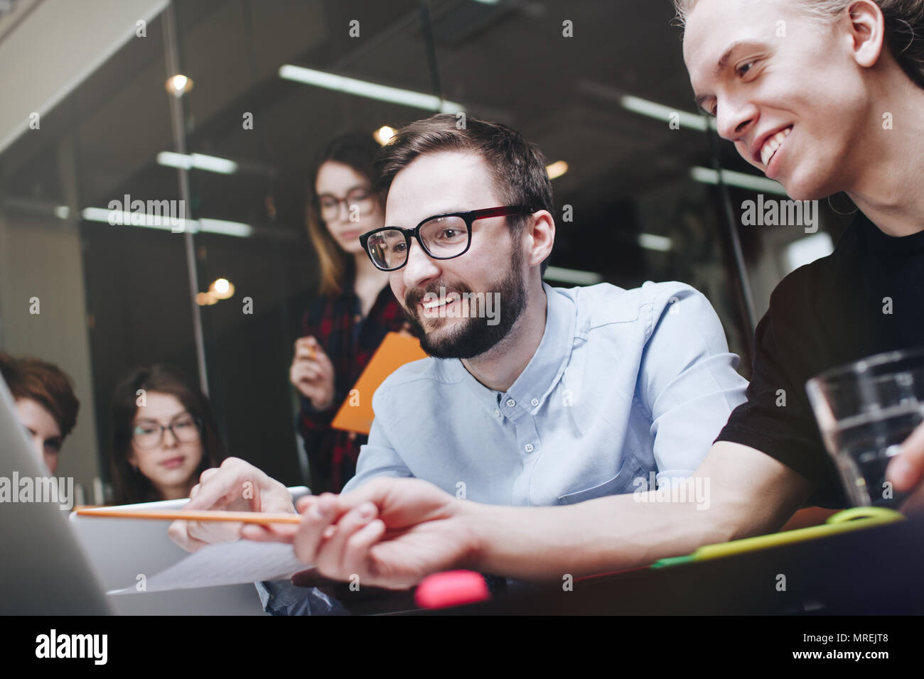 Team of cheerful colleagues works on modern gadgets. Crew of coworkers ...