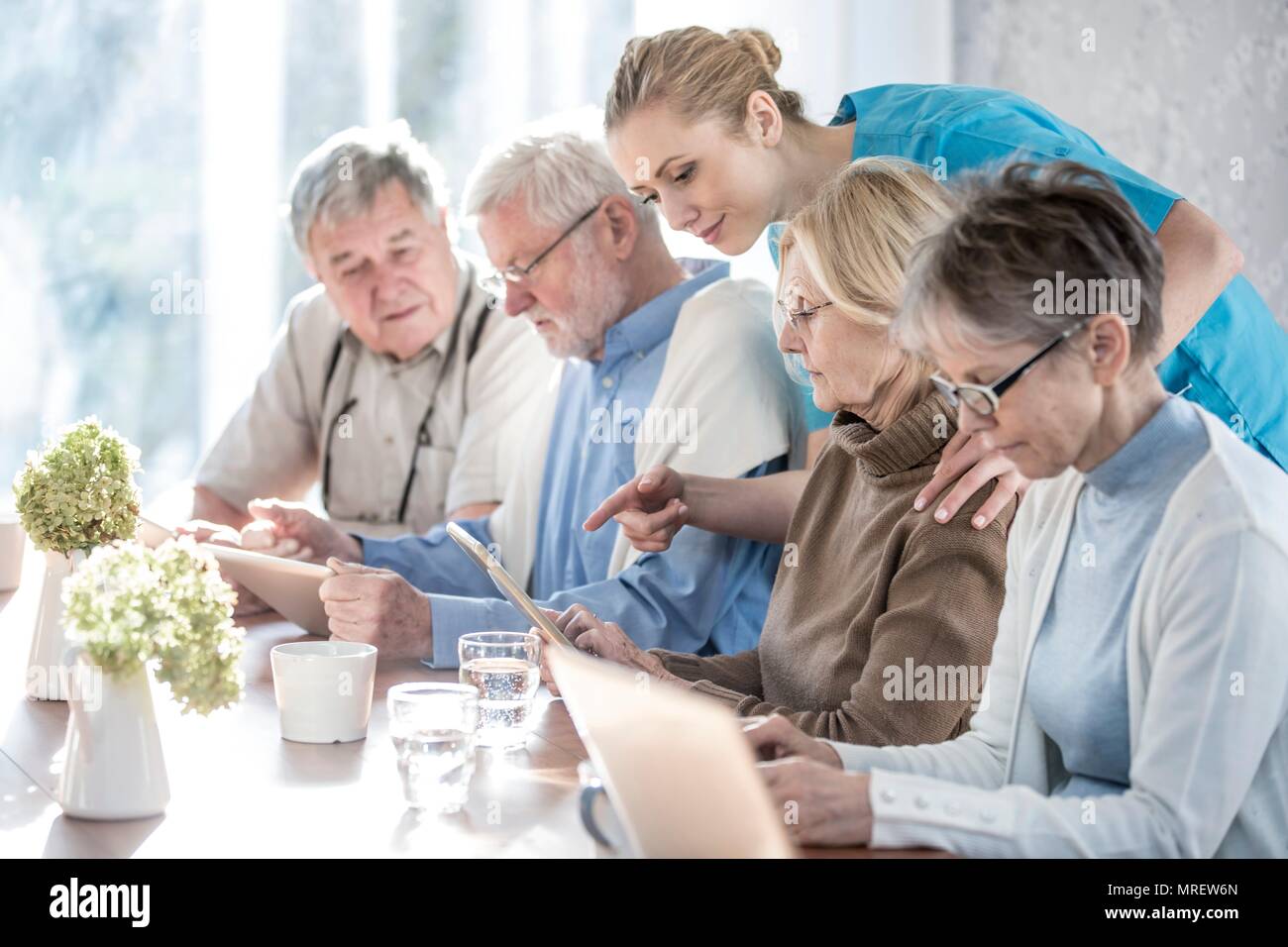 Senior adults in care home using digital tablets with care worker Stock ...
