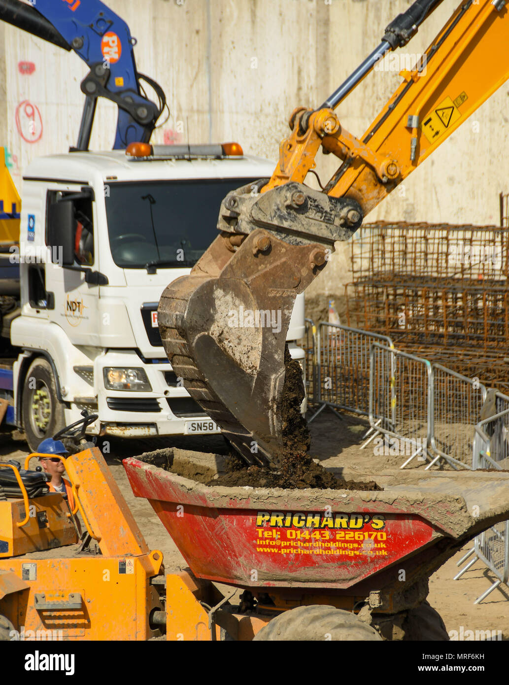 Close up of an excavator bucket tipping earth into a dumper on the site ...