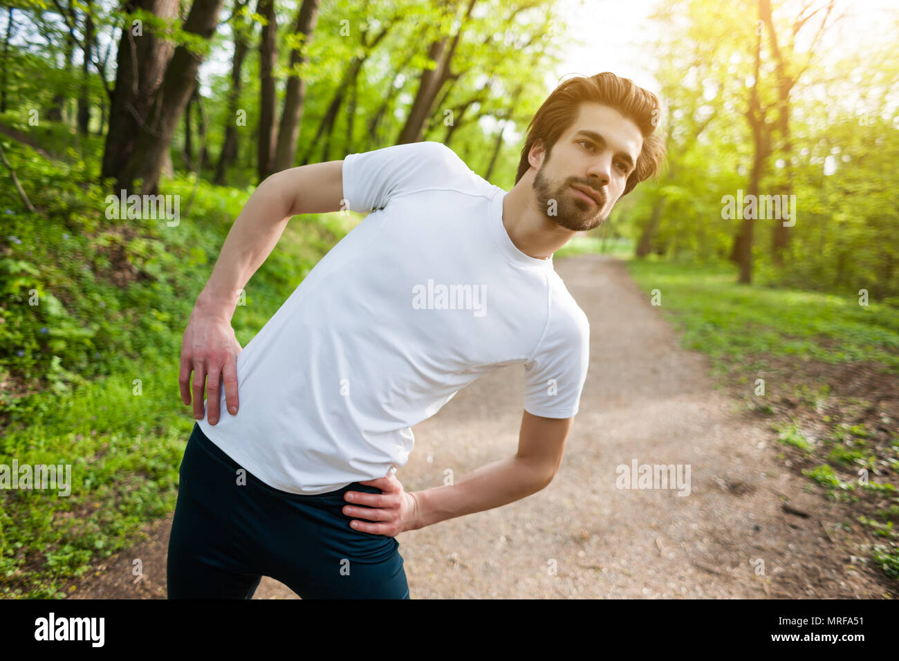 Young man is exercising in park. He is stretching his body Stock Photo ...