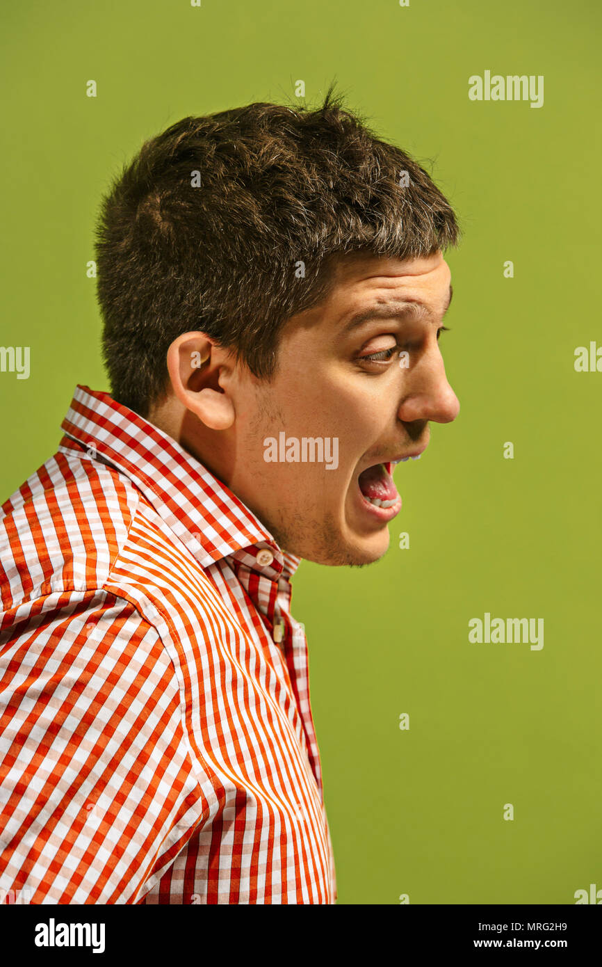 The young emotional angry man screaming on green studio background ...