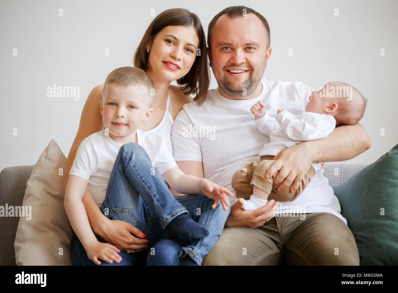 Image of smiling parents with two young sons sitting on sofa Stock ...