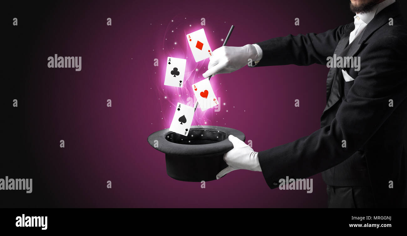 Magician with white gloves conjuring playing cards from a cylinder with ...