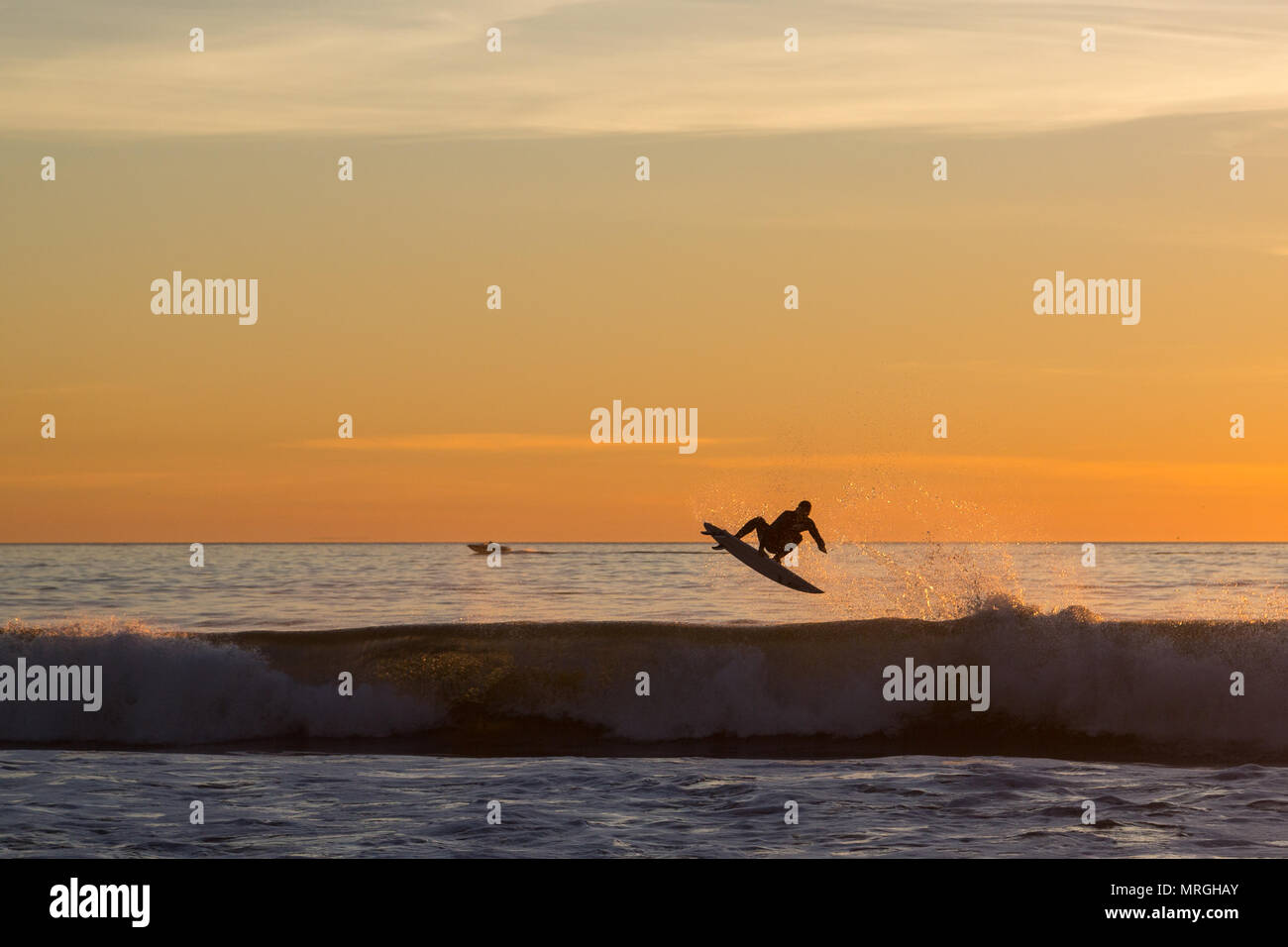 A surfer launches a big aerial maneuver (an air reverse), creating ...