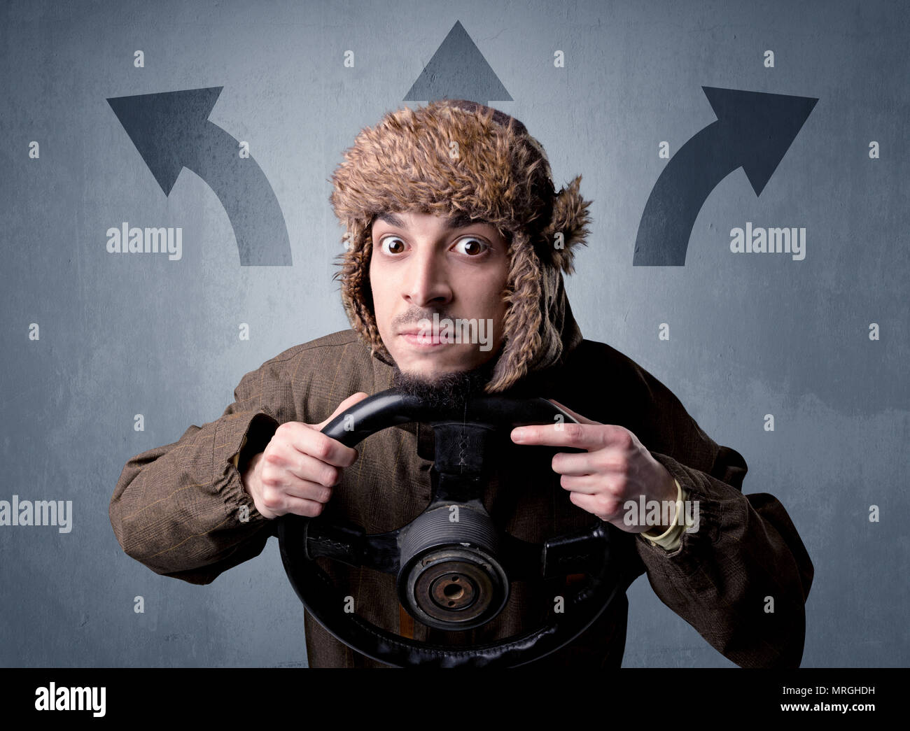 Young man holding black steering wheel with three arrows above his head ...