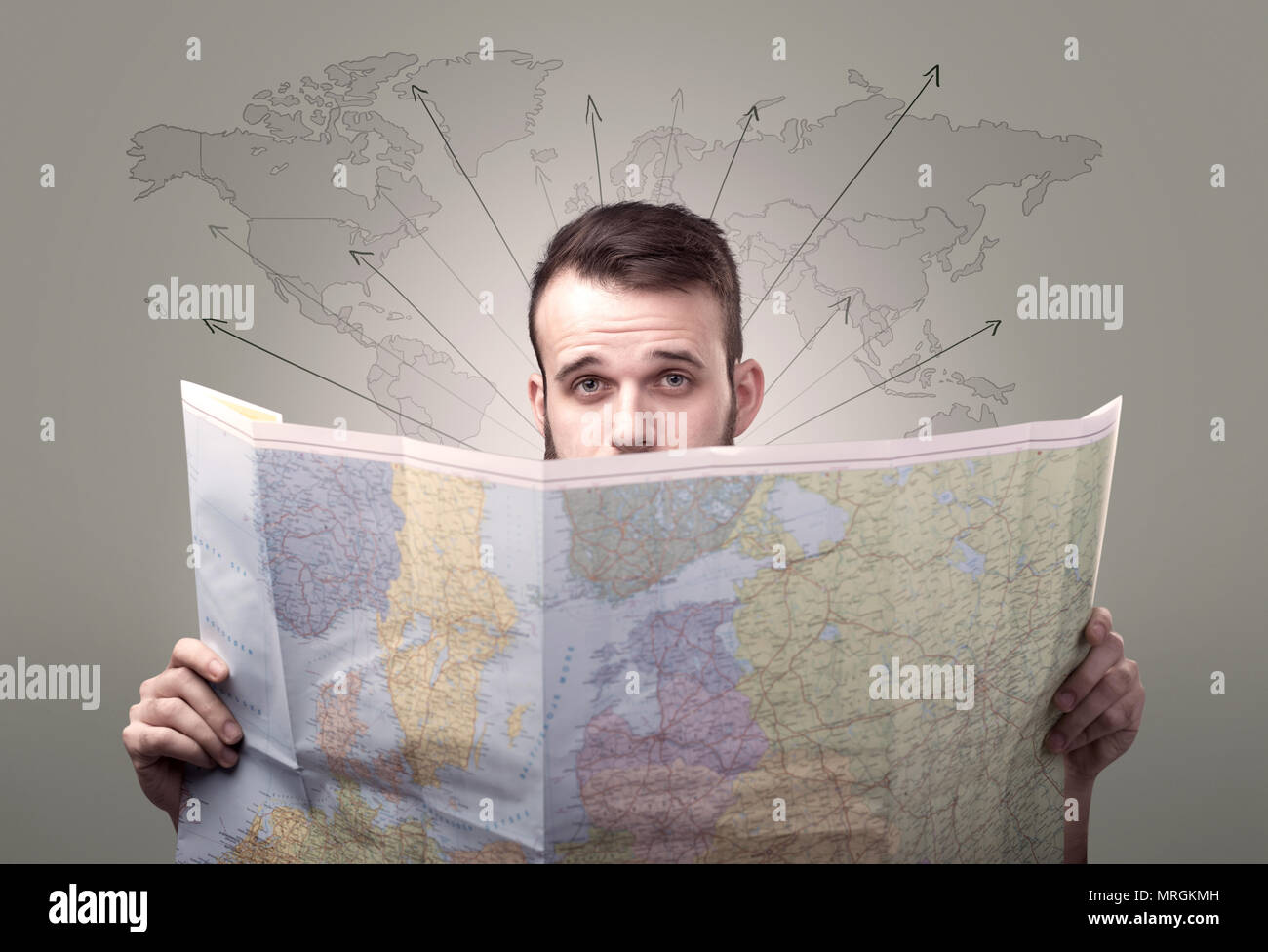 Handsome young man holding a map with world map and arrows behind him ...