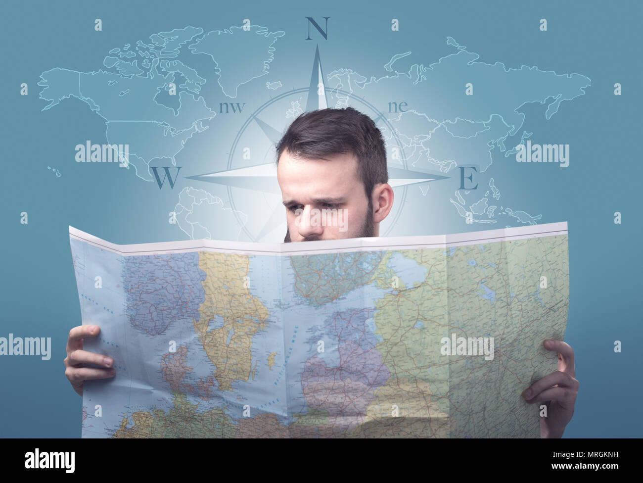 Handsome young man holding a map with a world map and a compass behind ...