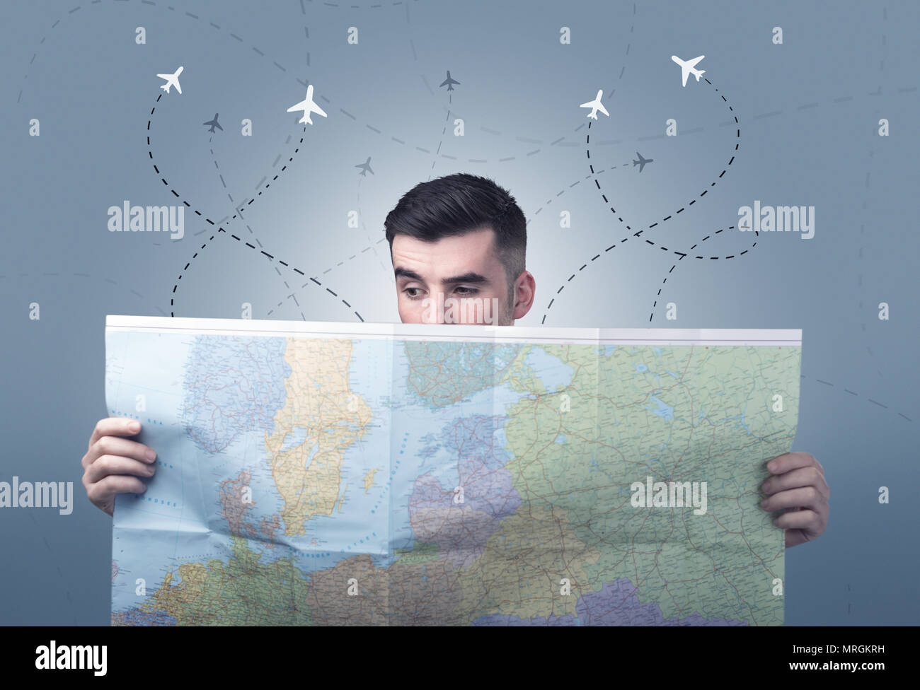 Handsome young man holding a map with little planes and their paths ...