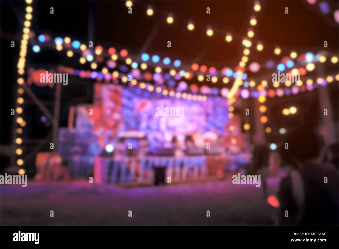 Light bokeh of people sitting in front of the stage at outdoor concert ...