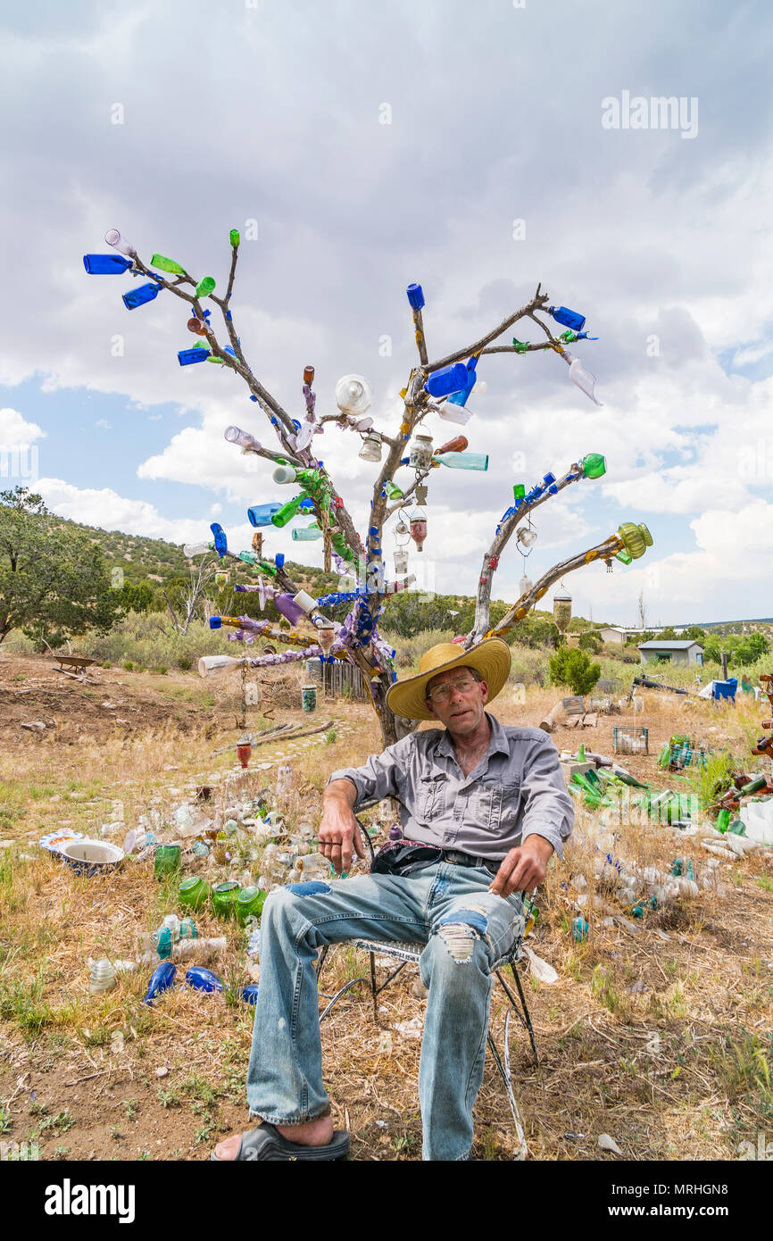 Tom Larson, the owner of the bottle house in Golden, New Mexico sitting ...