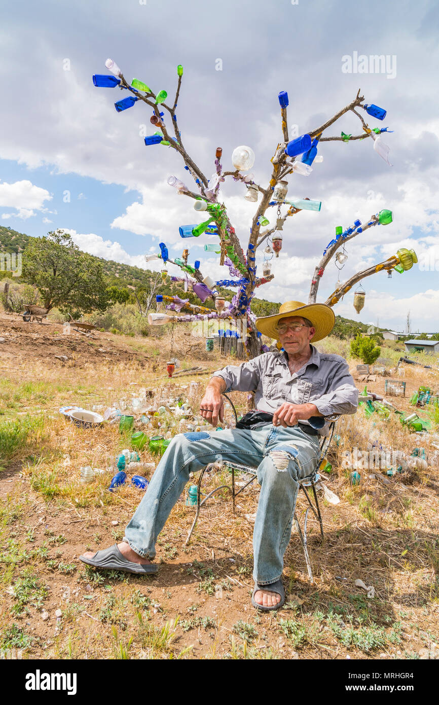 Tom Larson, the owner of the bottle house in Golden, New Mexico sitting ...