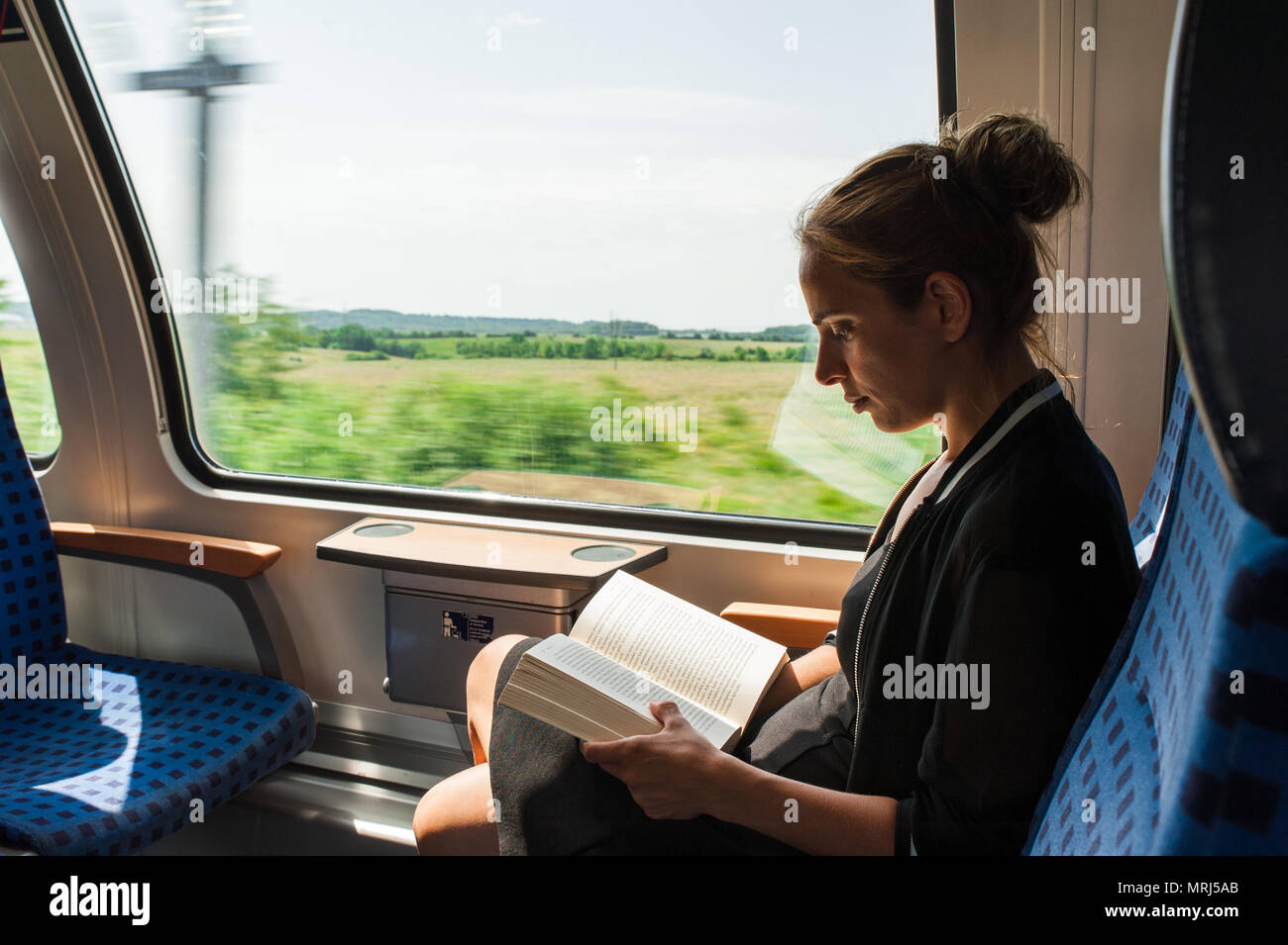 Young woman reading a book while travelling by train Stock Photo - Alamy