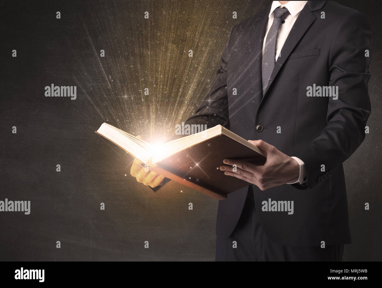 Man holding and reading a shiny book Stock Photo - Alamy