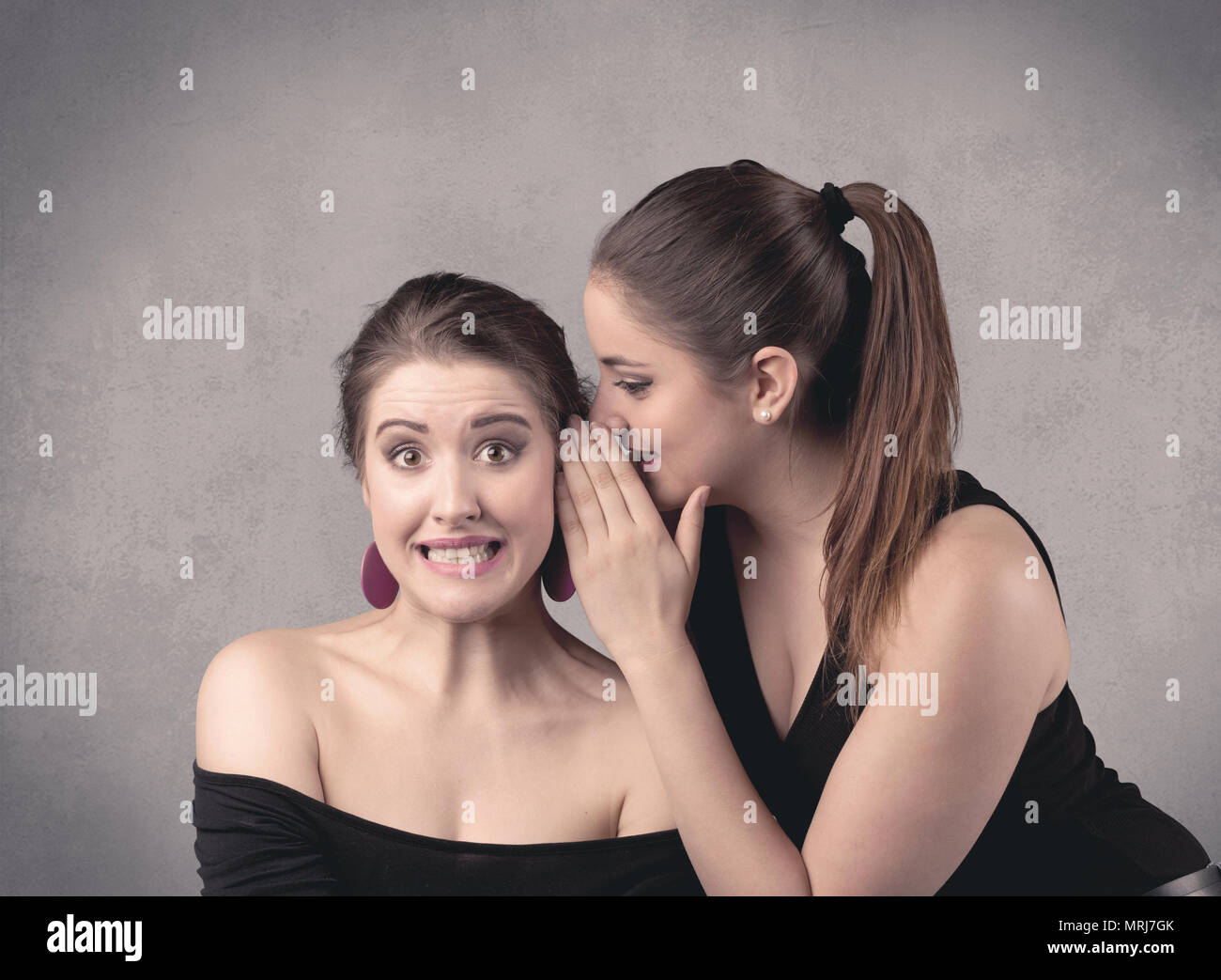 Two fancy dressed actress girls with long hair and make up whispering ...