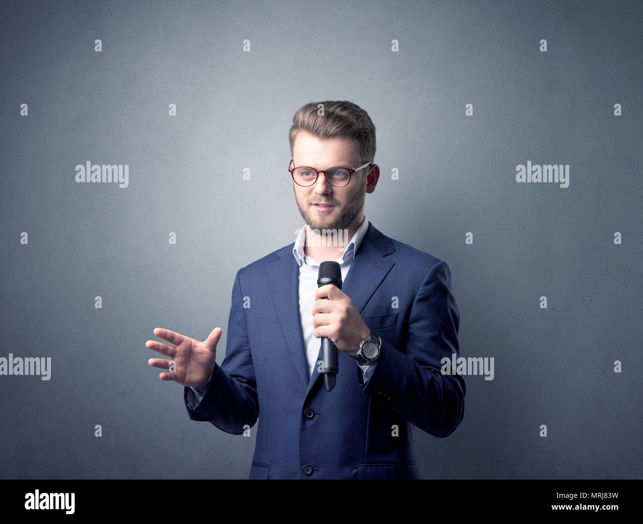 Businessman speaking into microphone with blue background Stock Photo ...