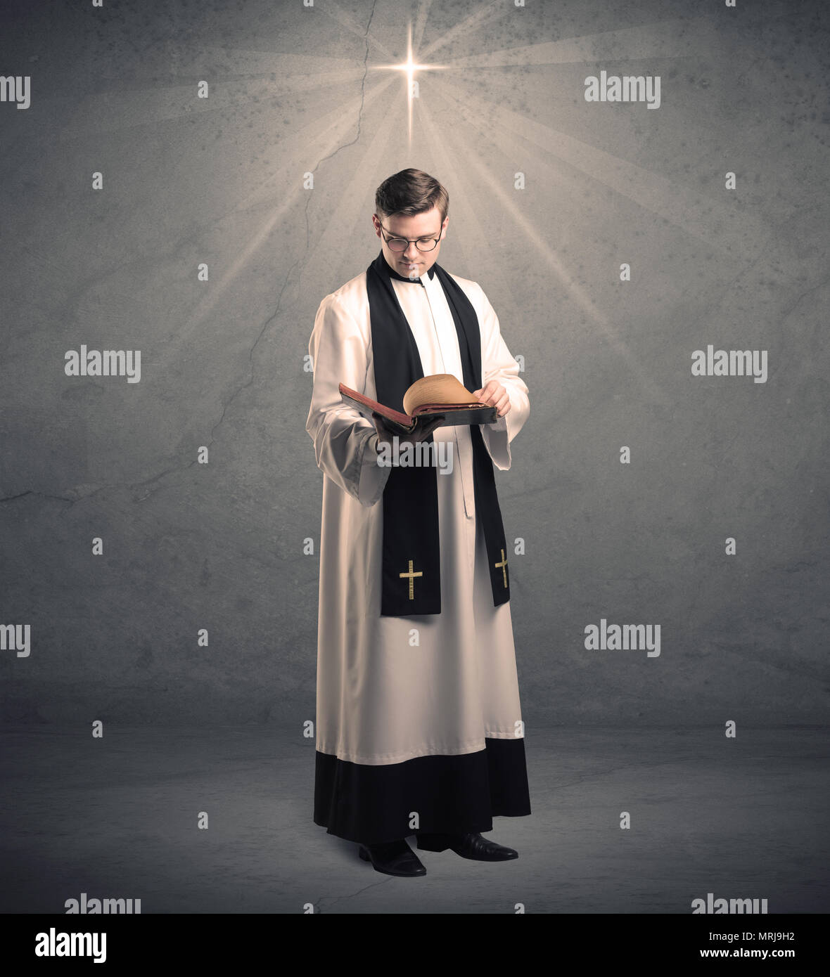 A young male priest in black and white giving his blessing in front of ...