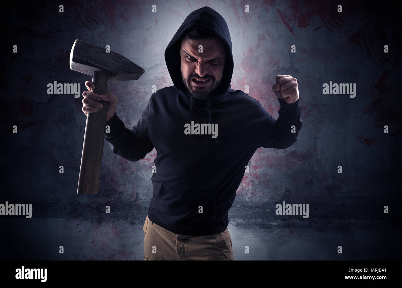 Armed rude assassin in an empty bloody room concept with gun ax ...