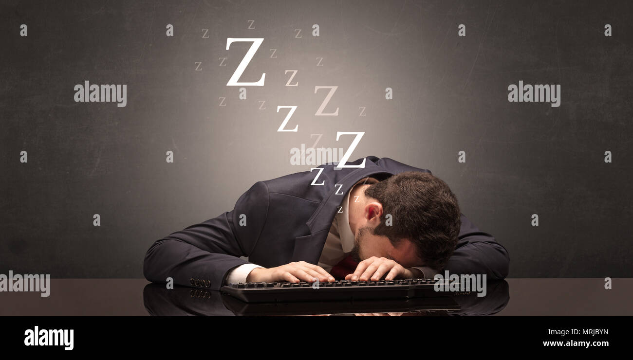 Young businessman fell asleep at the table on his keyboard concept ...