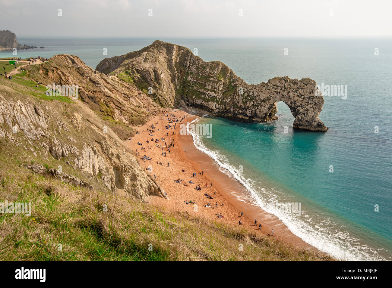 A high up view of the famous limestone arch Durdle Door and golden sand ...