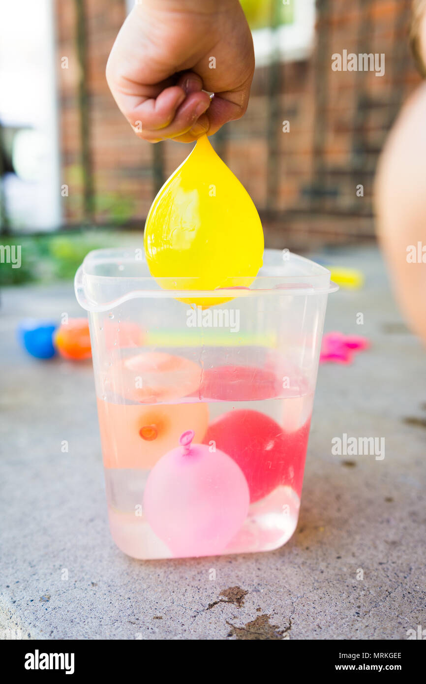 Child's hand pulling a water balloon out of a tub of water Stock Photo ...