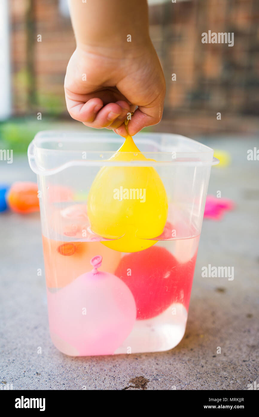 Child's hand pulling a water balloon out of a tub of water Stock Photo ...