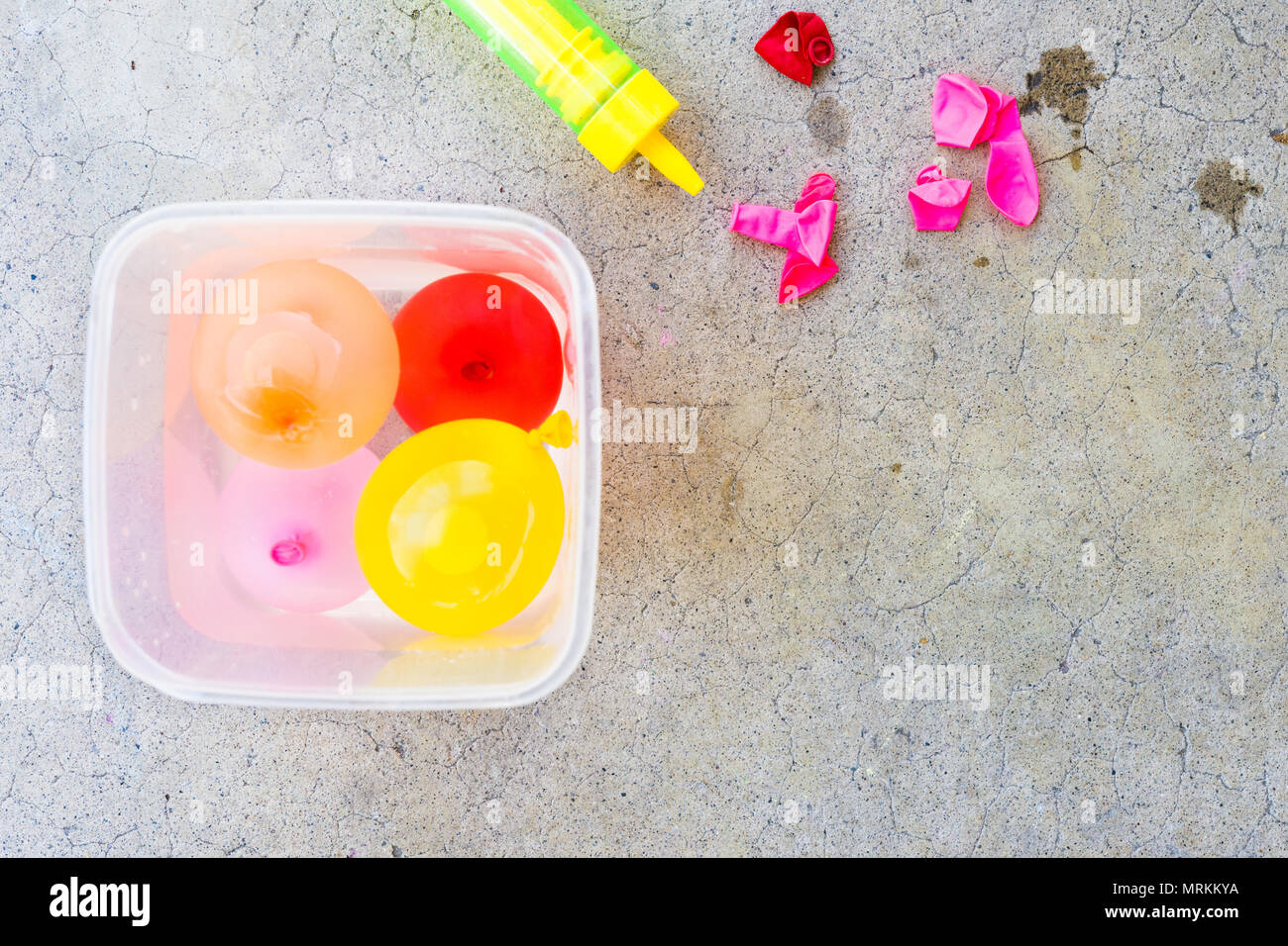 Overhead of small tub of water balloons and empty ones ready to be ...