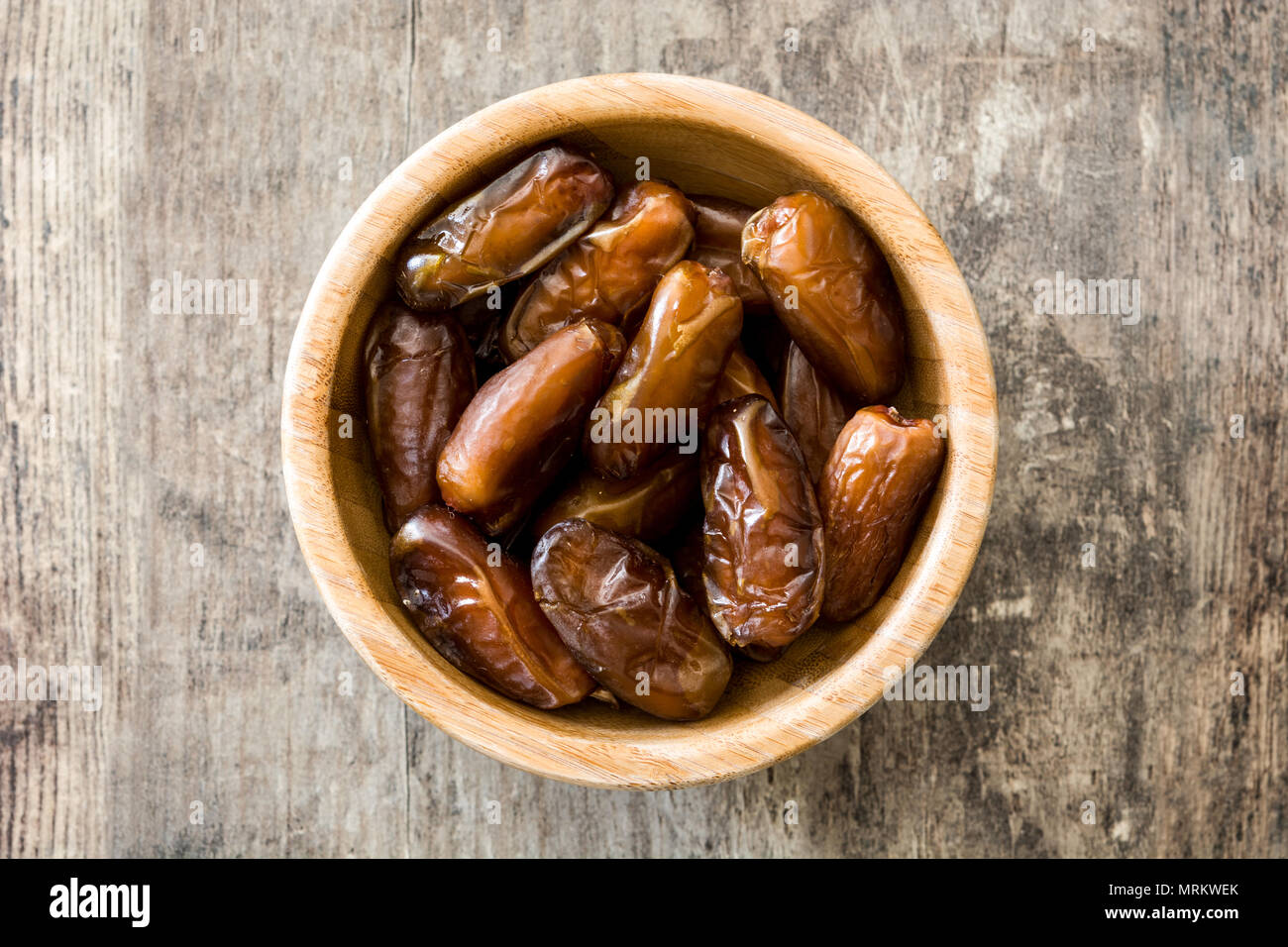 Dates food in wooden bowl on wooden table. Top view Stock Photo - Alamy