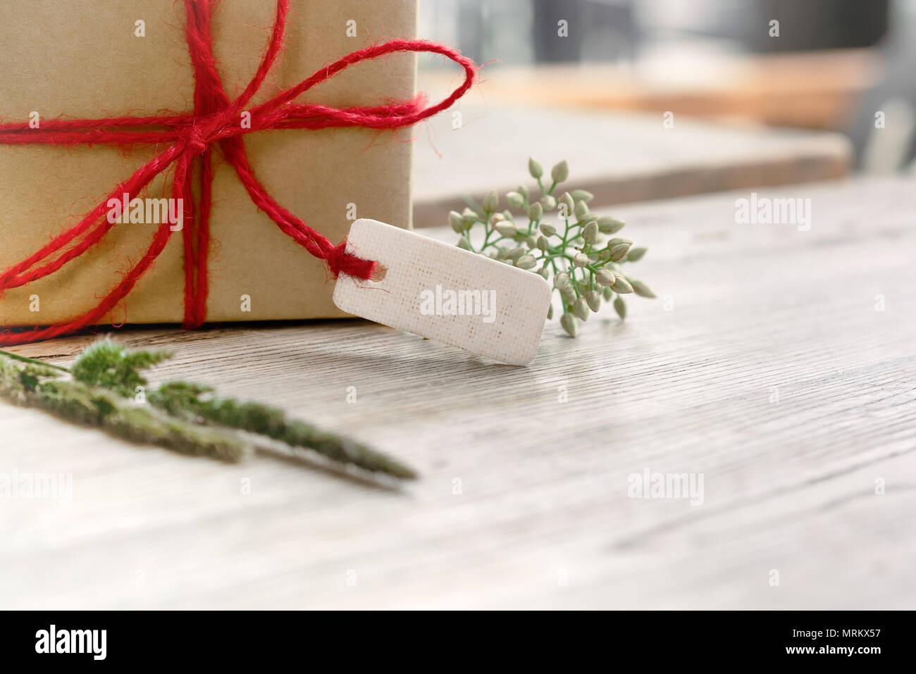 Gift box with blank tag and flower on wooden table, copy space for ...