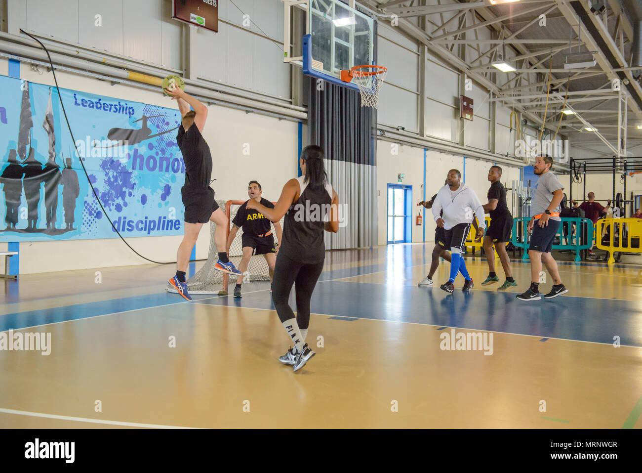 A U.S. Soldier jumps to throw a ball as Soldiers and civilians with ...