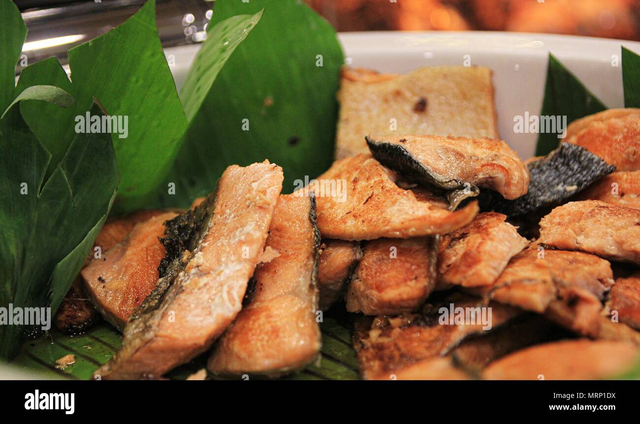 Crispy fried fish slices served in banana leaves and white plate Stock ...