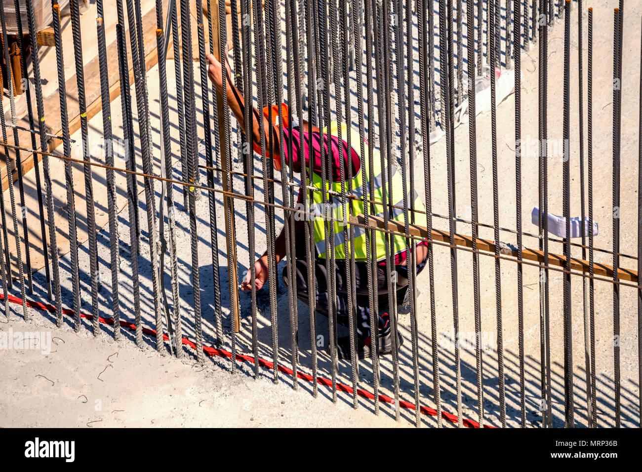 Worker measuring formwork for pouring concrete on metal rods ...