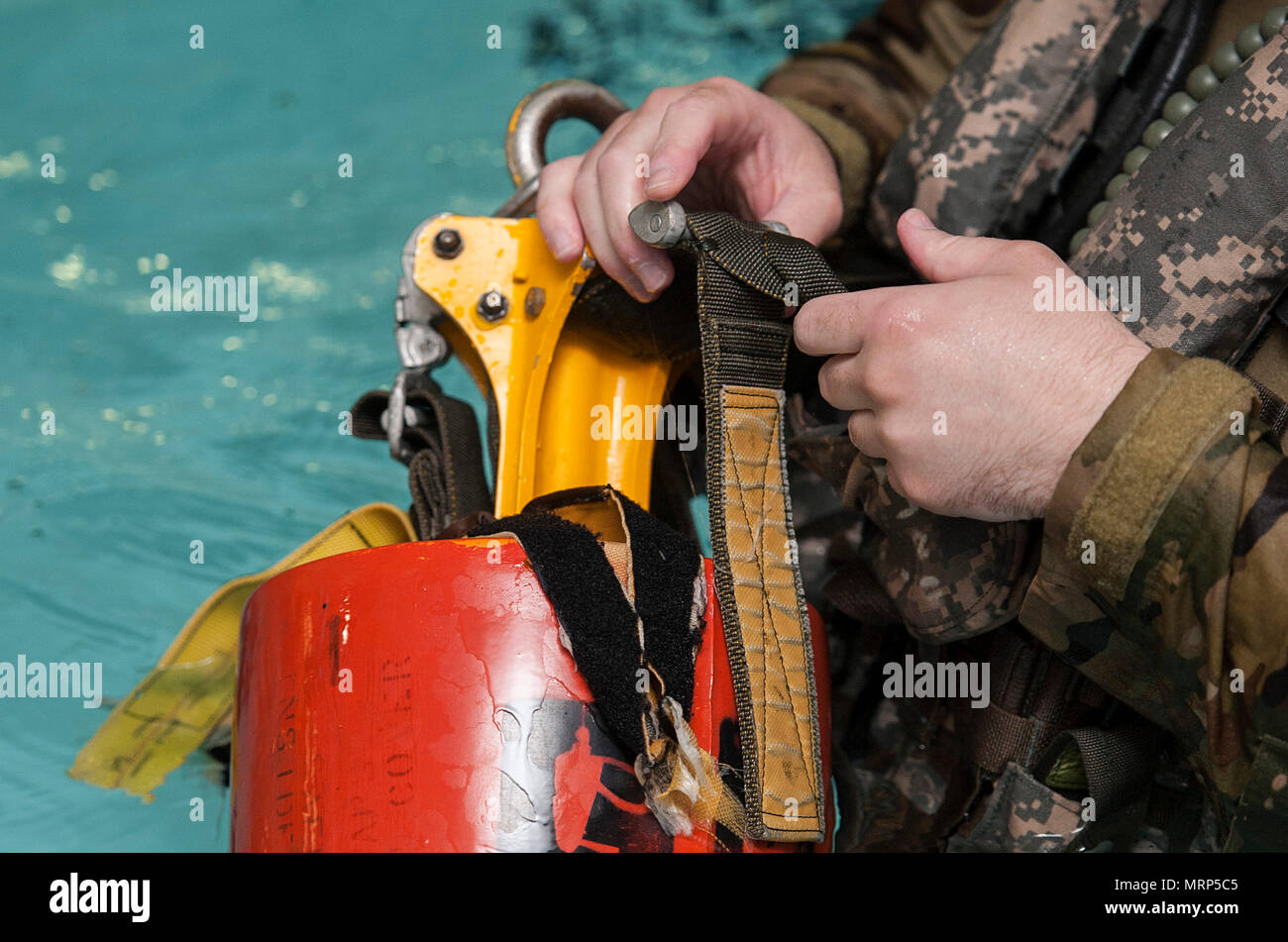 A 54th Helicopter Squadron Airman fastens a forest penetrator at Minot ...
