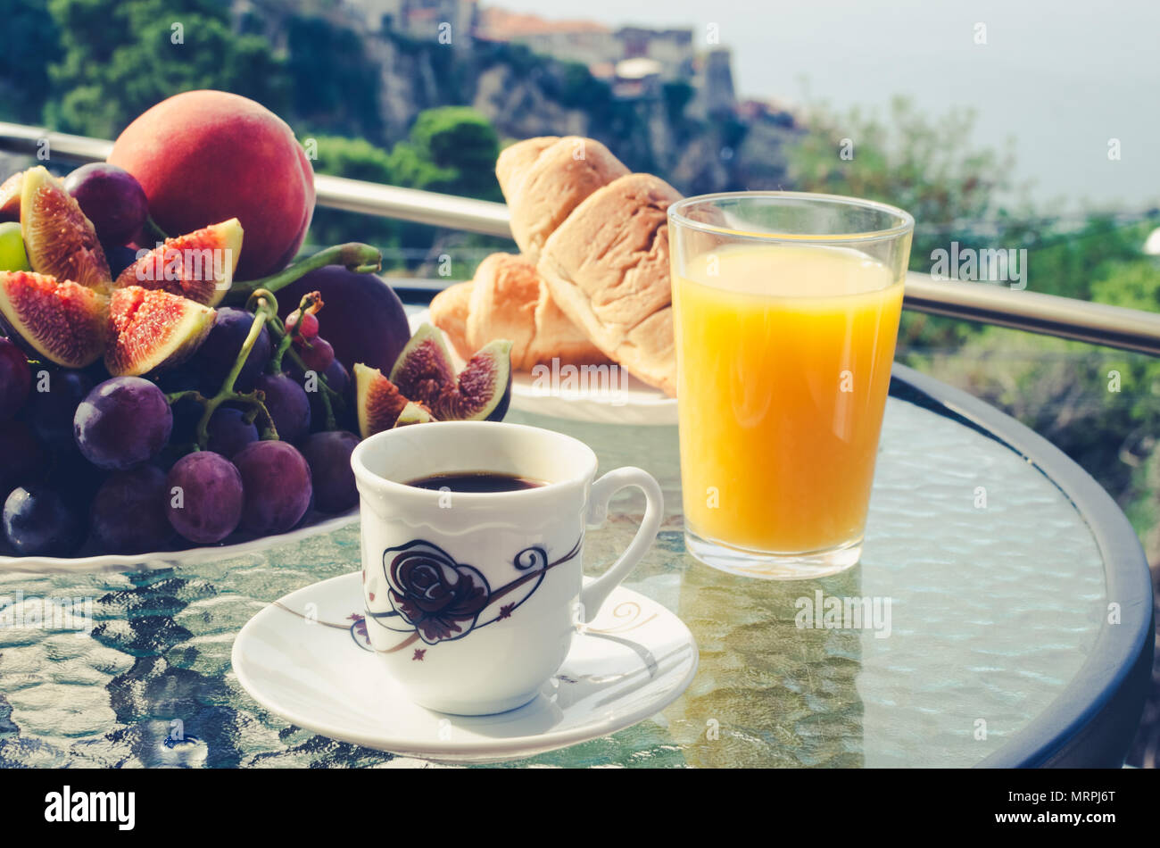Breakfast table with coffee, orange juice, fruits and croissants ...
