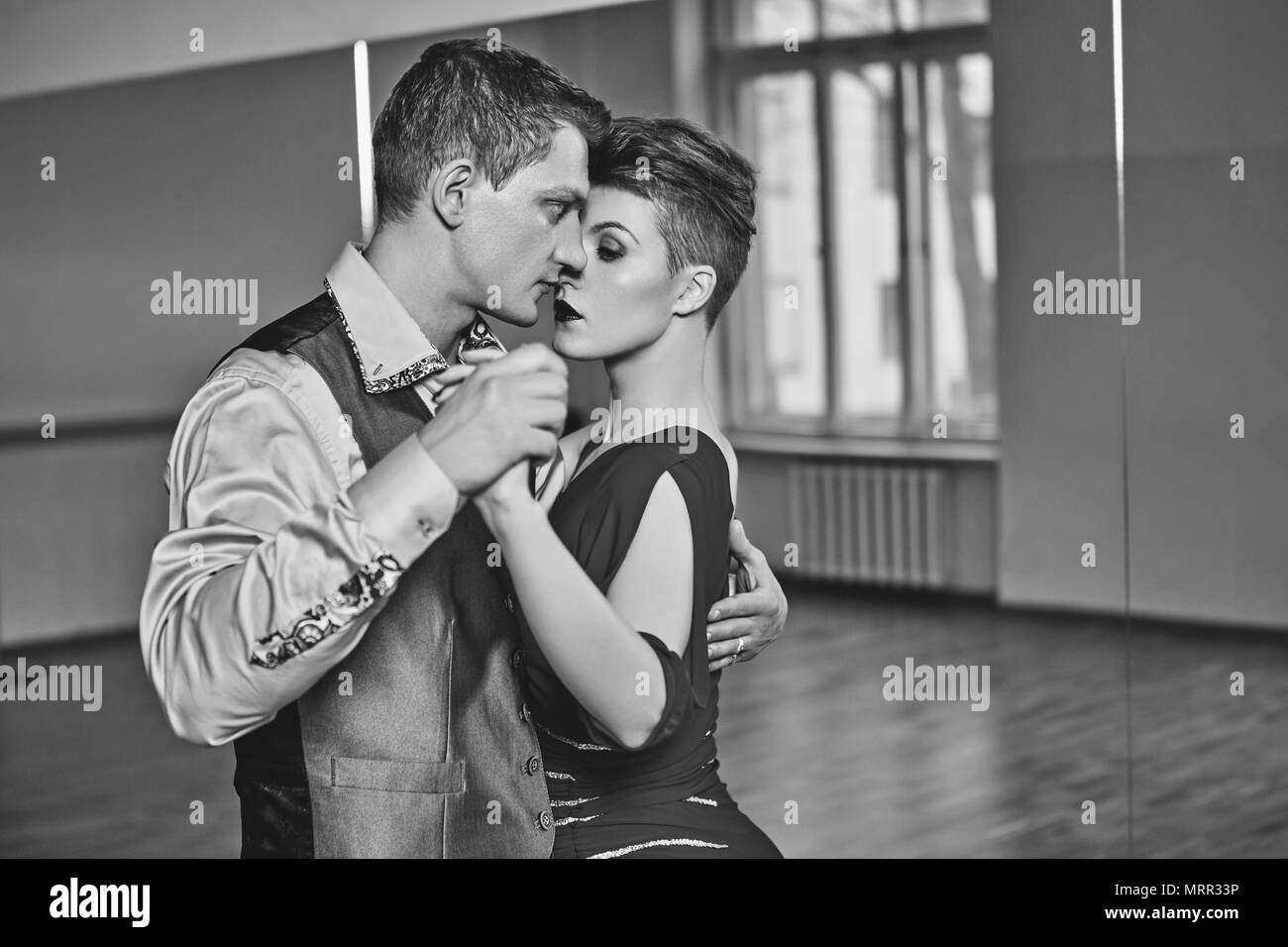 beautiful couple dancing tango. young woman in red dress and man in suit practicing in dancing ...