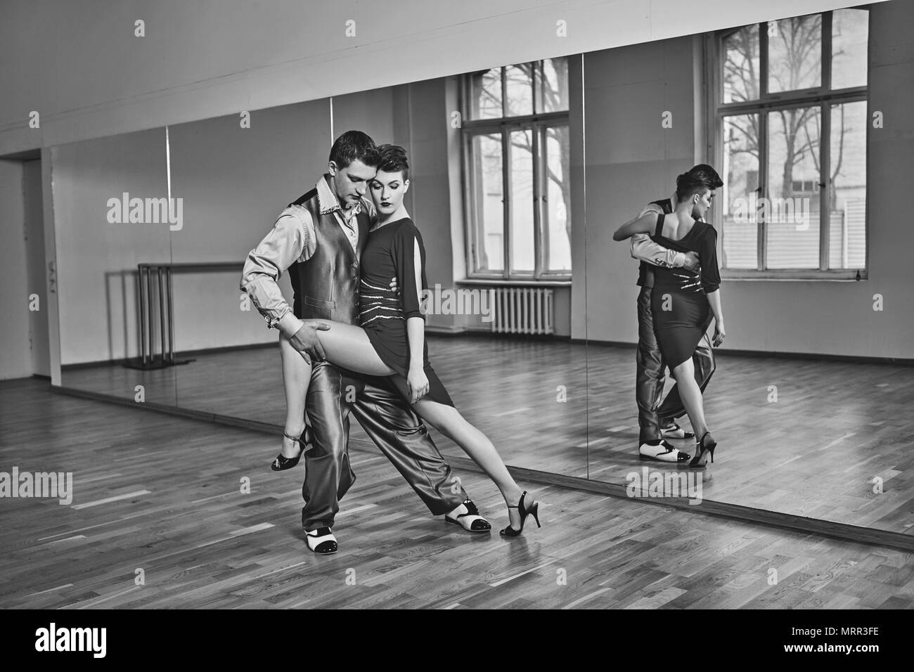 beautiful couple dancing tango. young woman in red dress and man in suit practicing in dancing ...