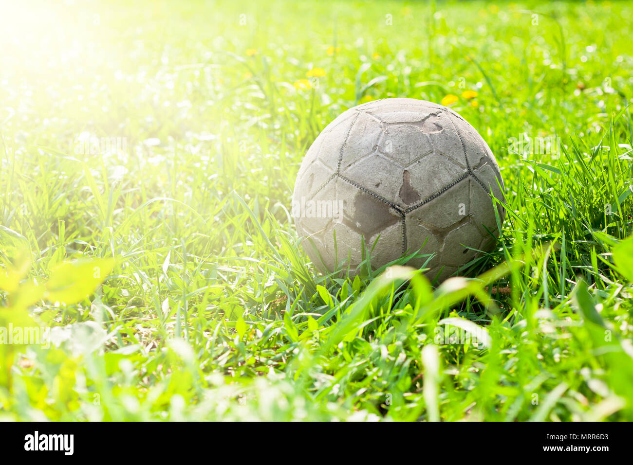 Old soccer ball forgotten in the green grass field. The football ...