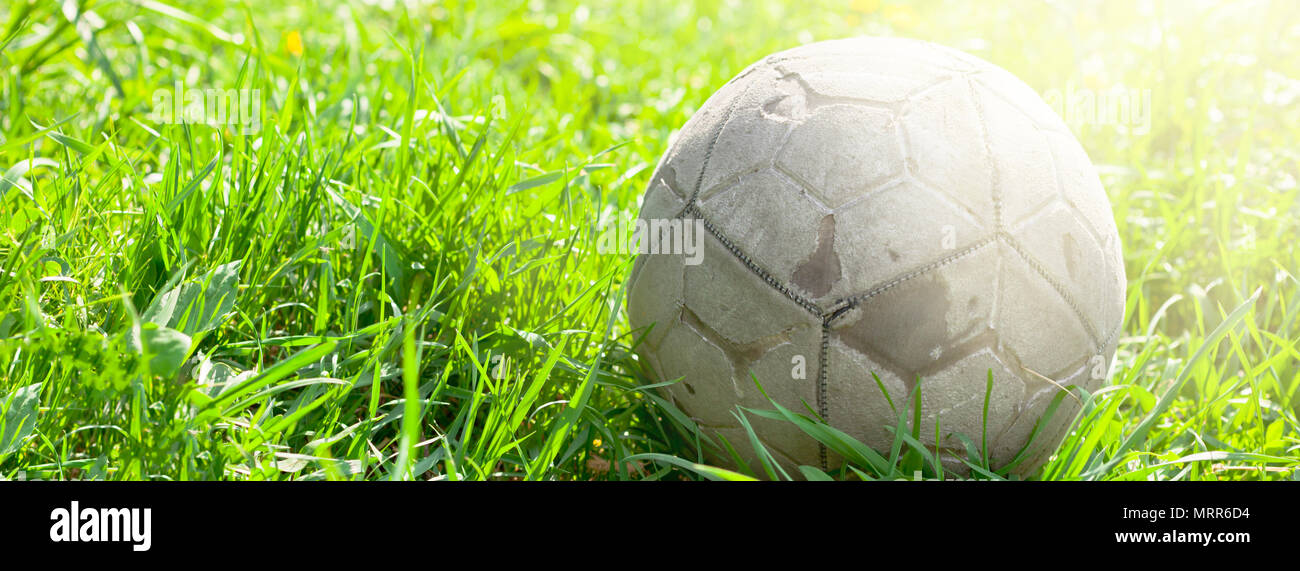Old soccer ball forgotten in the green grass field. The football ...