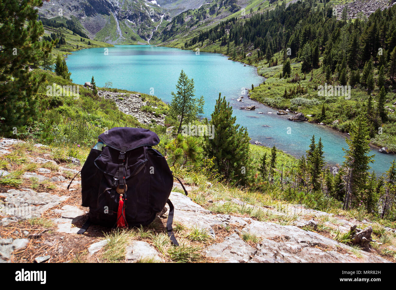Black Backpack lying on the stone against a mountain landscape with ...