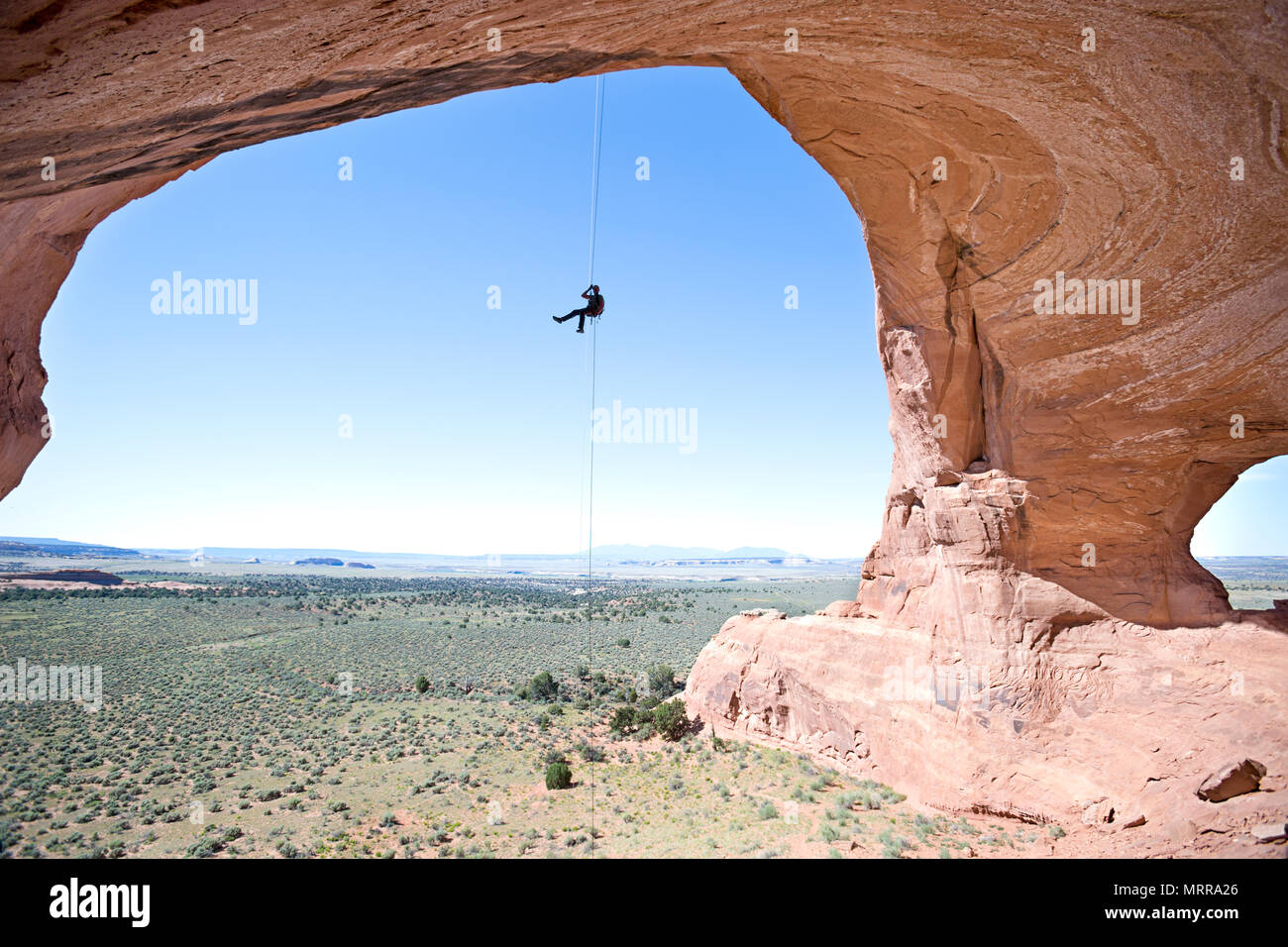 one man rappelling down Looking Glass Arch Stock Photo - Alamy