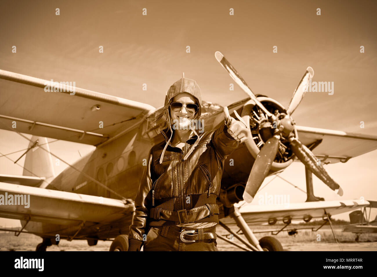 Portrait of beautiful female pilot with plane behind. Sepia photo Stock ...