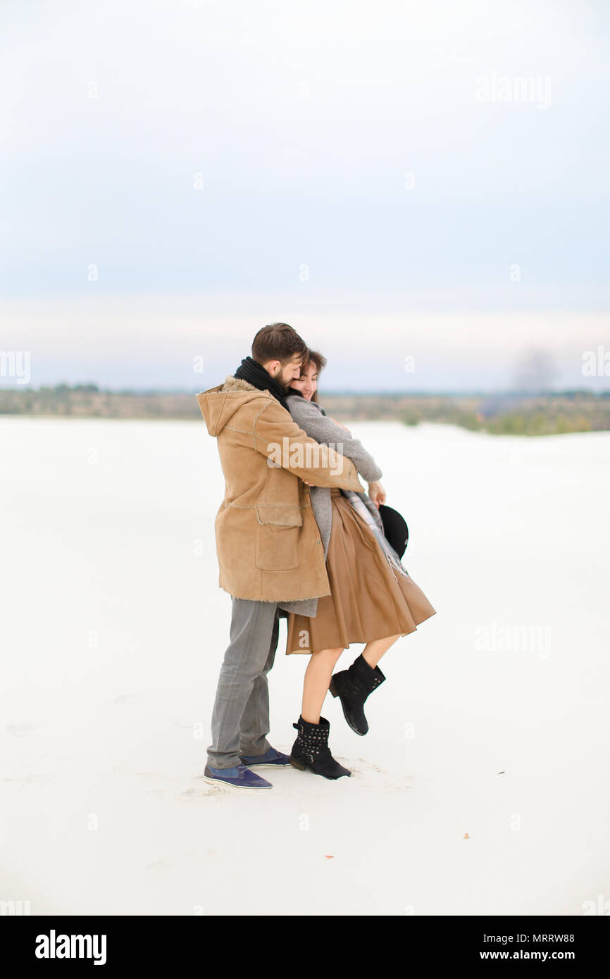European man hugging woman in snow winter background, wearing coat and ...