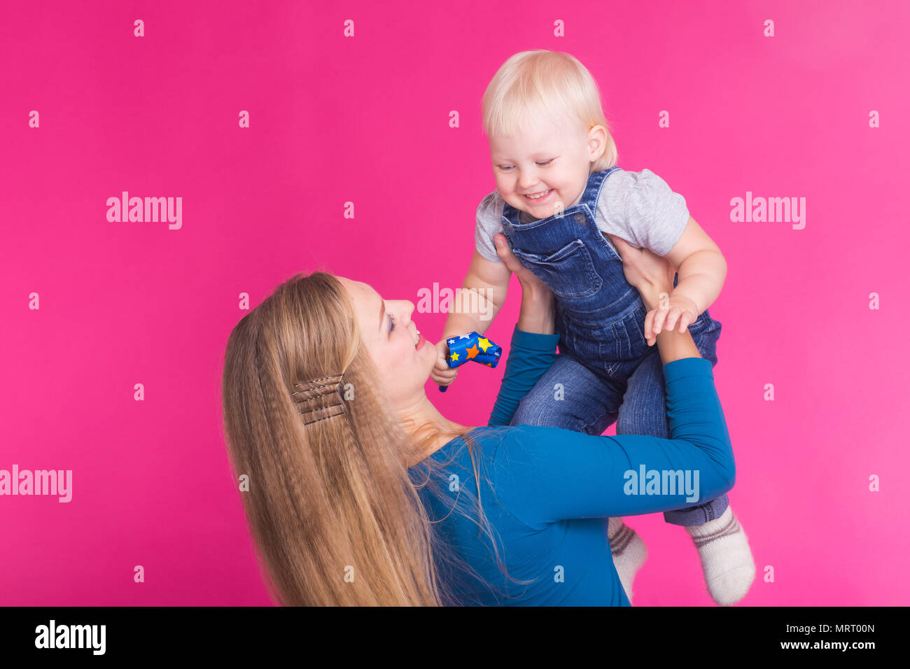 young mother and daughter having fun together on pink background Stock ...