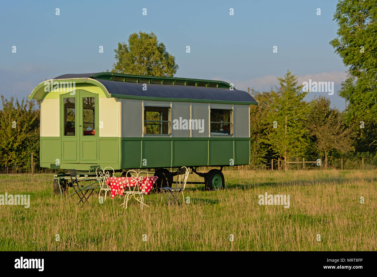 Romantic green painted wooden caravan with vintage table and chairs in ...