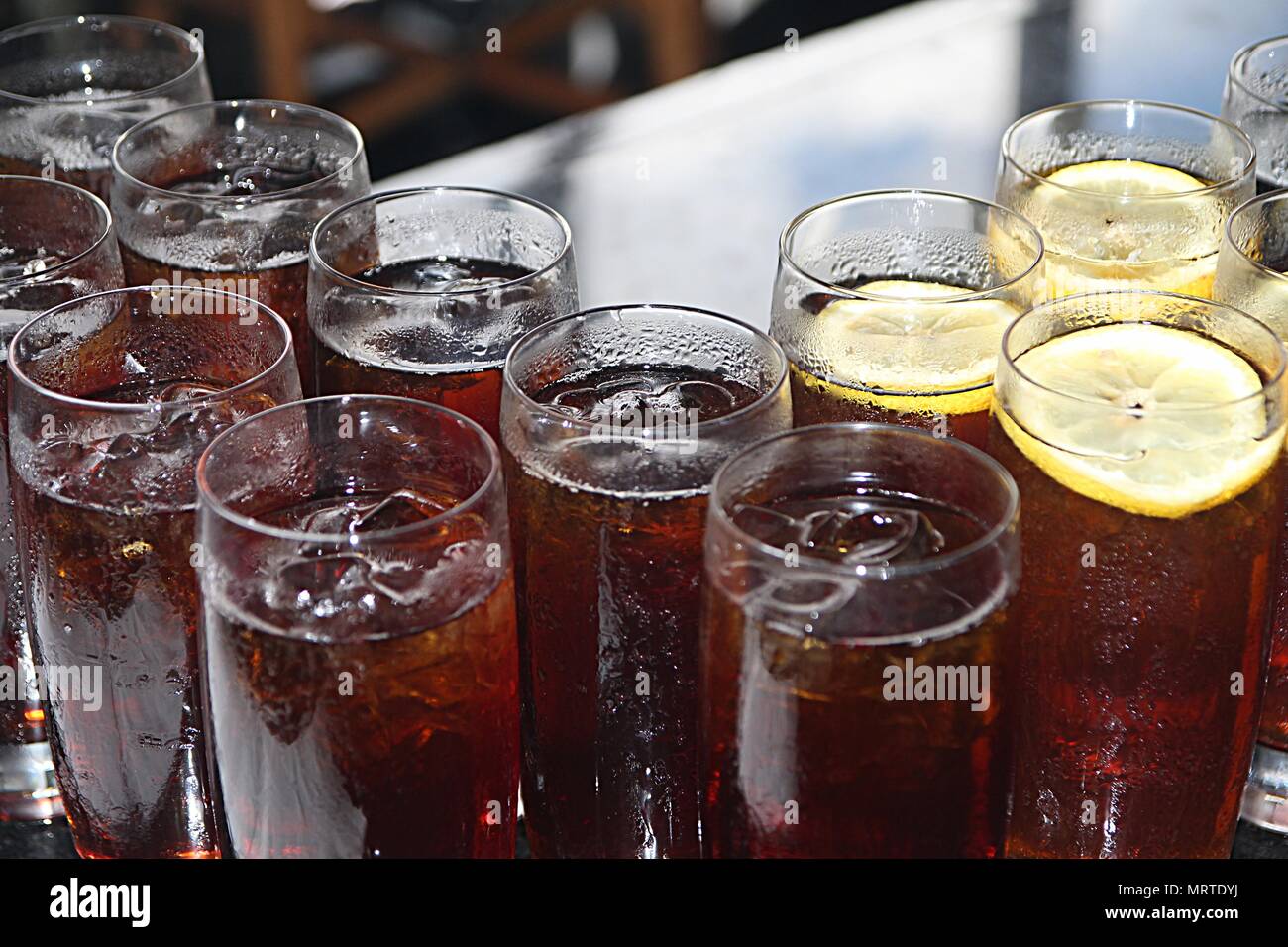 Several glasses of iced tea with and without lemon slices lined up ...