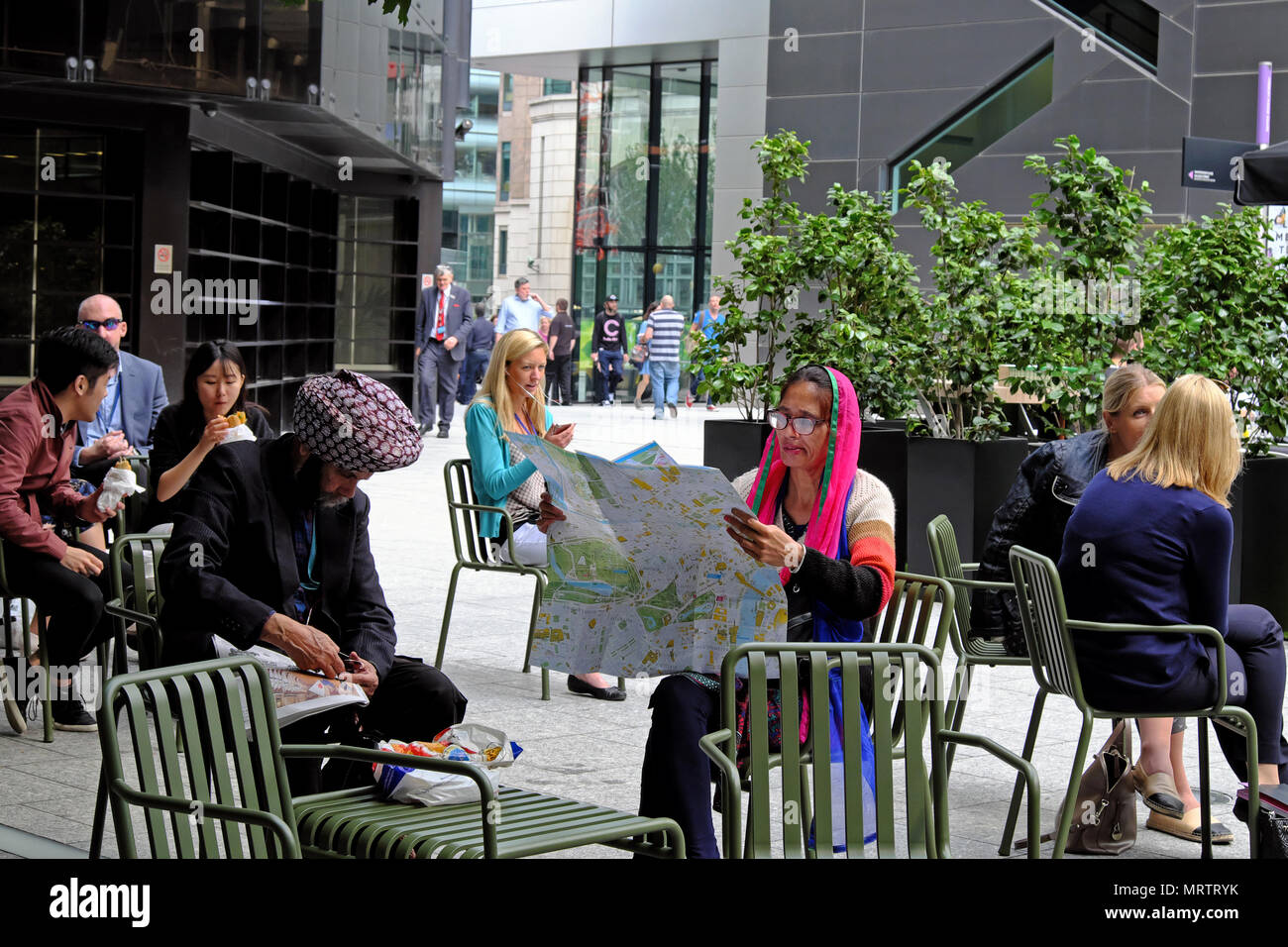 Tourists and City workers from diverse backgrounds sit in chairs and ...