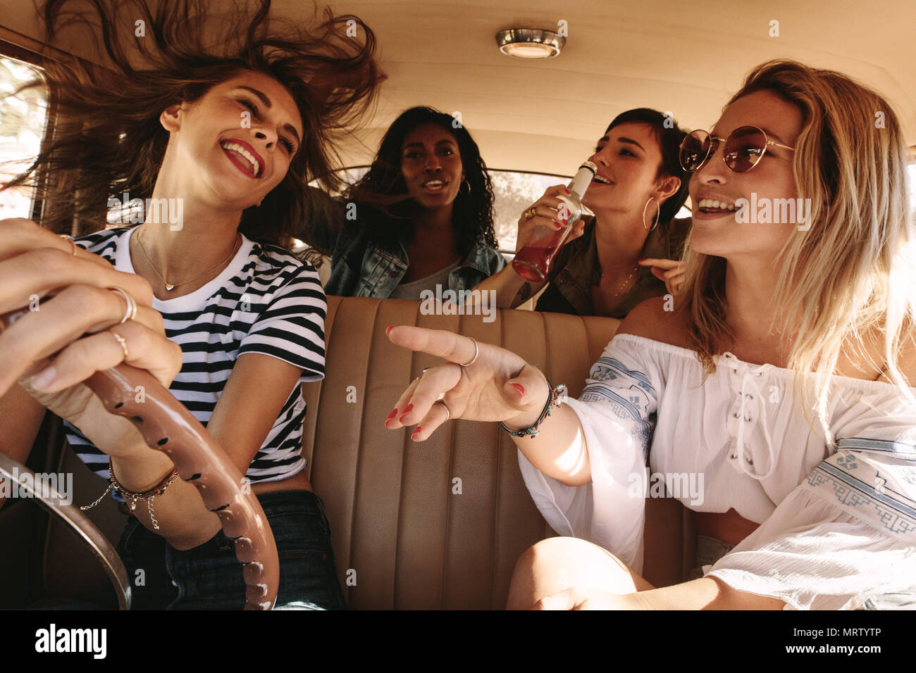 Group of happy young women laughing and enjoying in car during a road ...